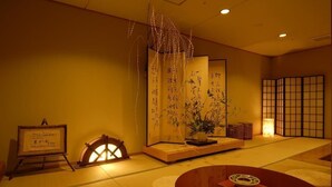 Um quarto japonês tradicional com tatames, uma mesa baixa, um painel shoji e um candeeiro pendente.