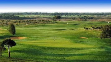 Um campo de golfe com vista clara para o fairway, bunkers de areia e um mastro de sinalização.