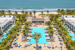 Resort com piscina central, espreguiçadeiras e palmeiras.