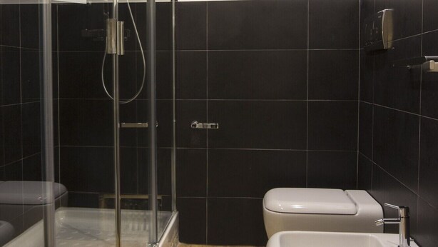 Uma casa de banho moderna com cabine de duche em vidro, duas pias e chão em madeira.