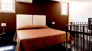 Quarto de hotel com cama, duas mesas de cabeceira, ar condicionado e janela.