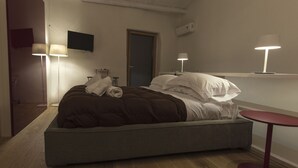 Quarto moderno com cama, abajures, televisão de tela plana e ar-condicionado.