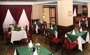 Uma área de refeições com mesas postas, cadeiras e um buffet.