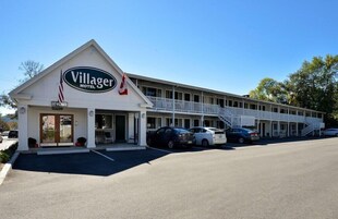 Um motel com um letreiro chamativo, uma galeria coberta e estacionamento.
