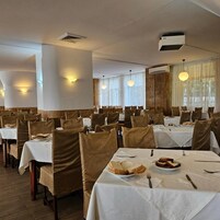 Um restaurante com várias mesas, cadeiras e uma ventilação no teto.