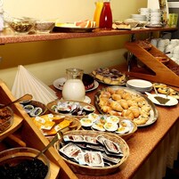 Buffet com diversos alimentos, incluindo doces, frutas e acompanhamentos.