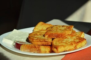 Uma fatia de pão com leite frita, acompanhada de manteiga e geleia.