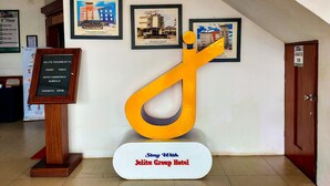 Uma área de recepção com uma grande escultura amarela, quadros nas paredes e uma placa do Hotel Jelita Tanjung.