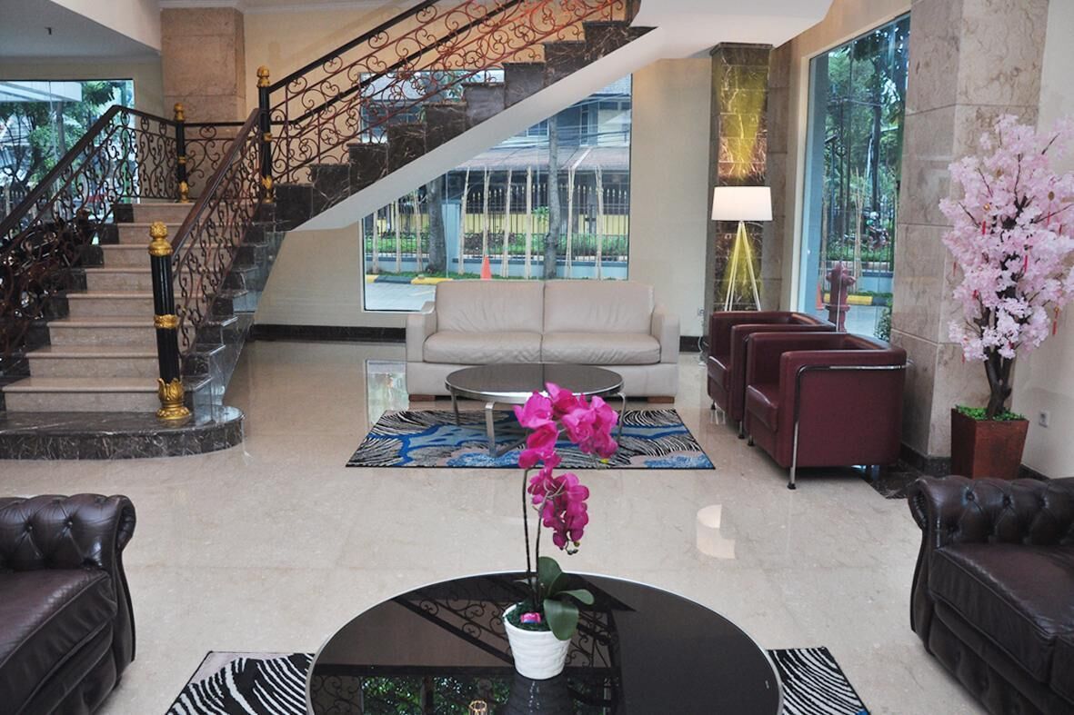 Um hall de entrada com escadaria de mármore, um sofá, uma mesa de centro e uma orquídea em vaso.