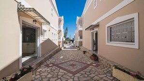 Uma rua estreita com calçada de pedra, edifícios de ambos os lados e floreiras ao longo do caminho.
