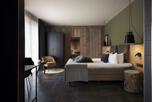 Quarto moderno com cama, cadeira, guarda-roupa e mesa de cabeceira.