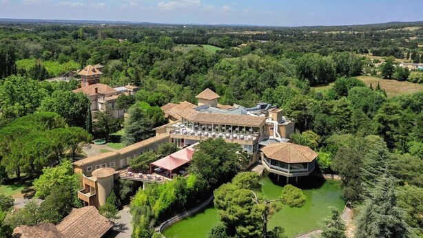 Um grande resort com vários edifícios, um pátio central e uma paisagem exuberante ao redor.