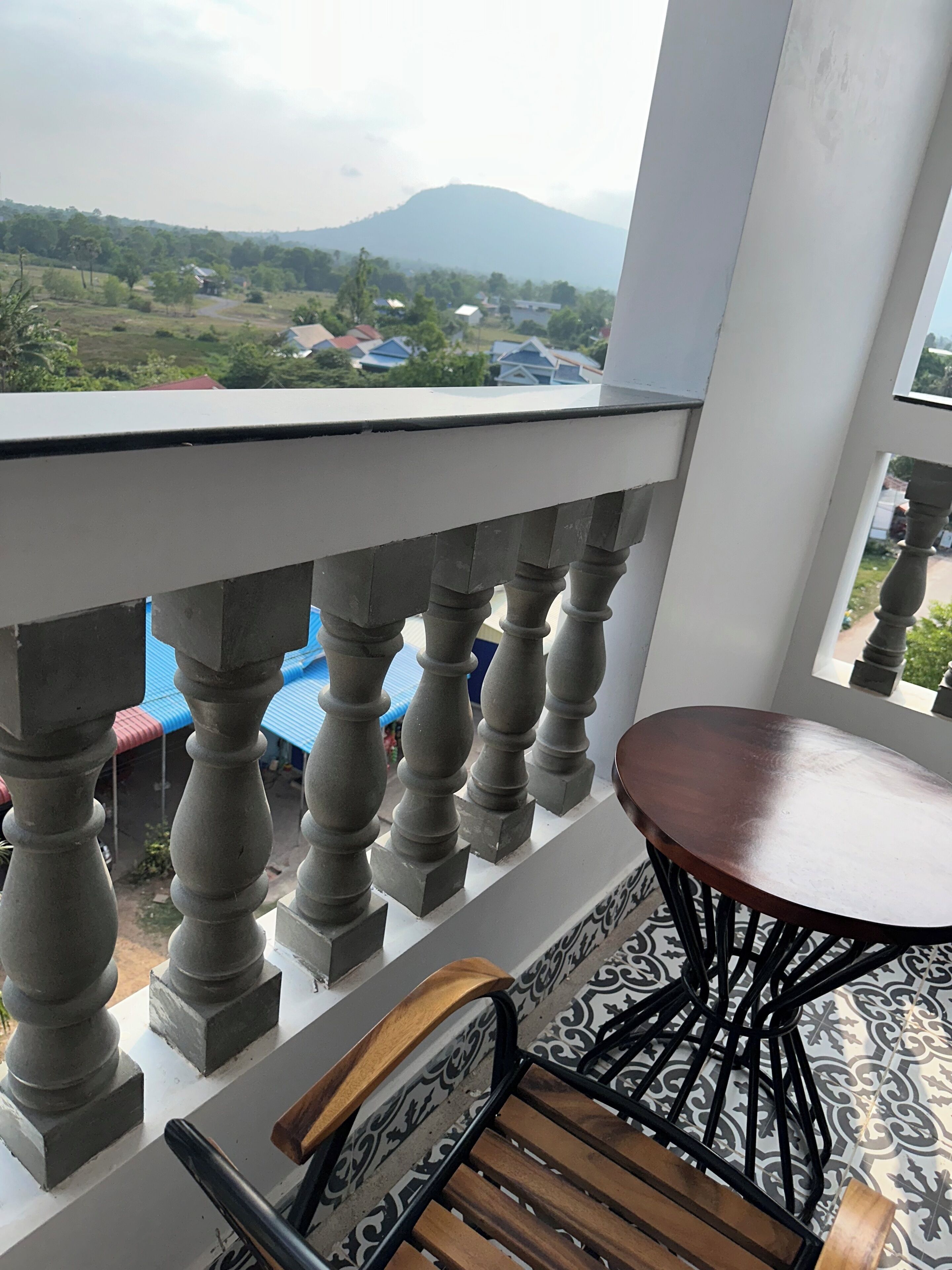 Uma varanda com vista para uma montanha, uma mesa e uma cadeira.