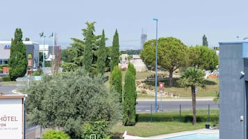 Hotel com piscina, rodeado por vegetação e vista para a paisagem urbana.