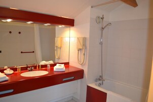 Casa de banho com lavatório vermelho, toucador branco e chuveiro com porta de vidro.