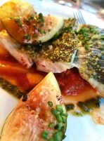 Prato com filés de peixe, possivelmente temperados com ervas, acompanhado de uma fatia de tomate e um pedaço de pão.