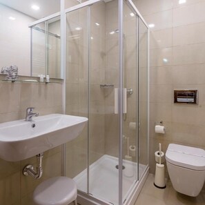 Uma casa de banho moderna com chuveiro de vidro, lavatório branco e sanita.