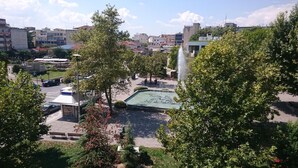 Um parque público com uma fonte, bancos e uma piscina.