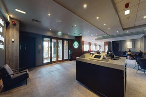 Um hall amplo com balcão de recepção, logotipo da Starbucks e área de estar.