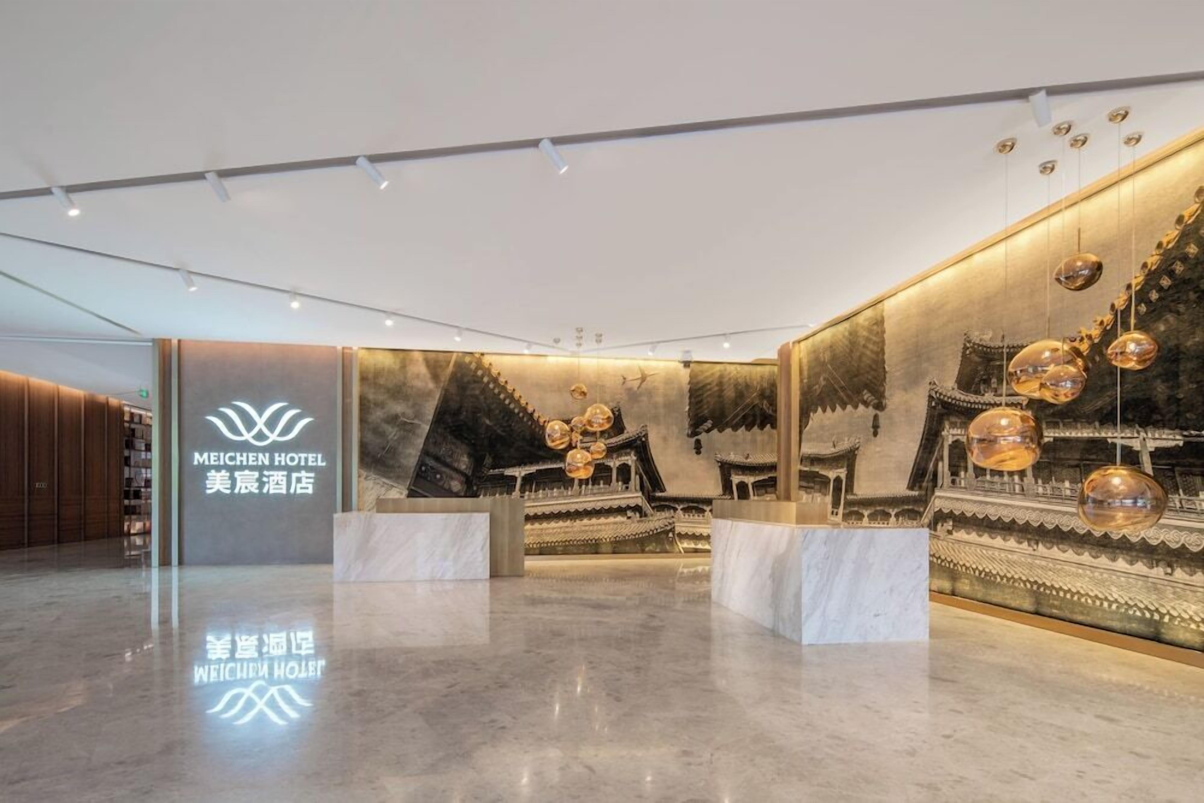 Um saguão de hotel moderno com um mural de arquitetura asiática tradicional, uma mesa de recepção e teto bem iluminado.