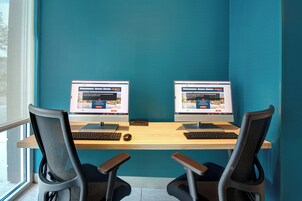 Um espaço de trabalho com dois computadores de mesa, um teclado, um rato e duas cadeiras de escritório.