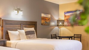 Quarto de hotel com cama, mesa de cabeceira, luminária e obra de arte na parede.
