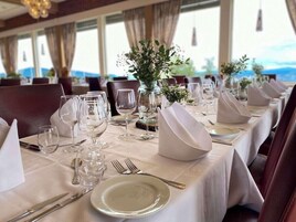 Mesa de restaurante posta com toalhas brancas, copos de vinho, pratos e talheres.
