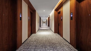 Um corredor de hotel com portas de madeira, carpete estampado e um longo vão.