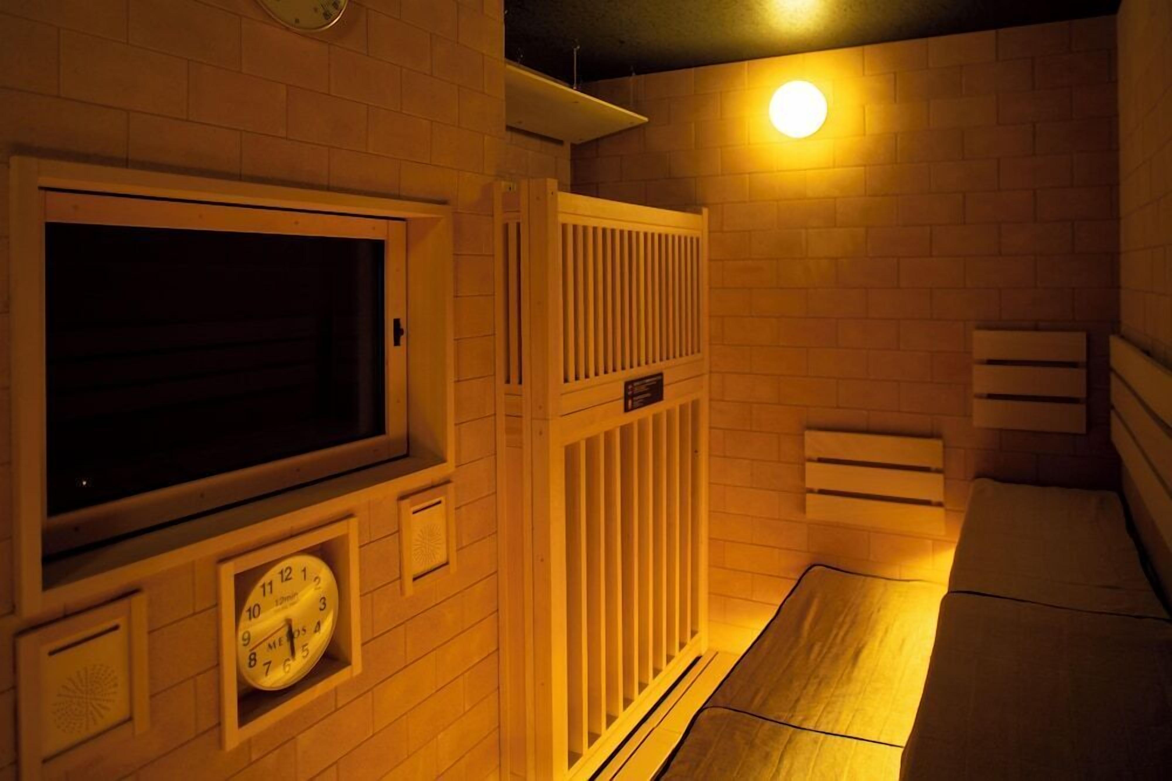 Quarto de hotel com uma janela grande, um relógio, um radiador e uma cama.