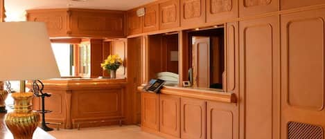 Um quarto amplo com painéis de madeira, uma janela grande e uma escrivaninha com abajur.