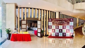 Um hall de hotel com carpete vermelho, balcão de recepção e escadaria.