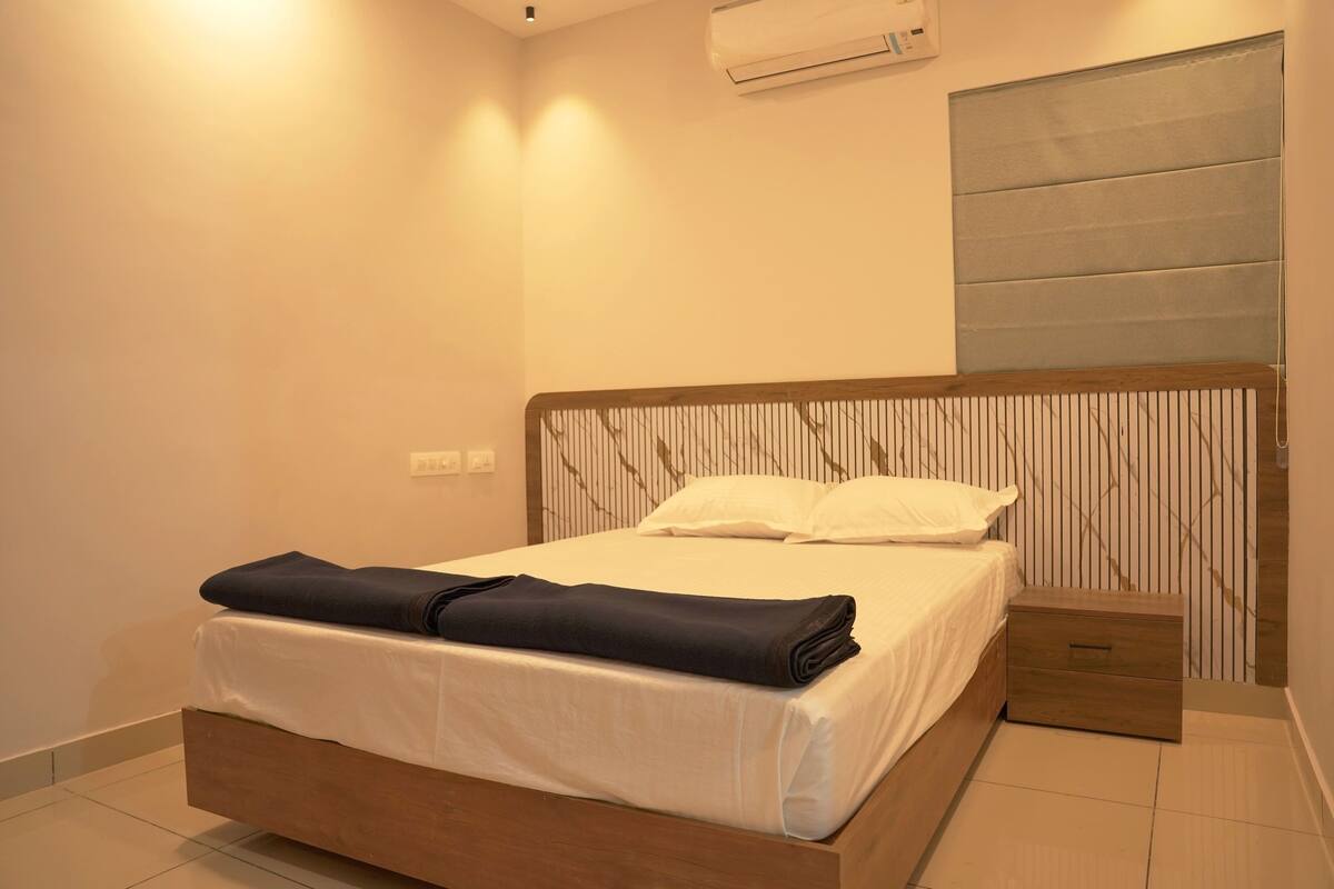 Cama bem arrumada com cabeceira de madeira e uma pequena mesa de cabeceira.