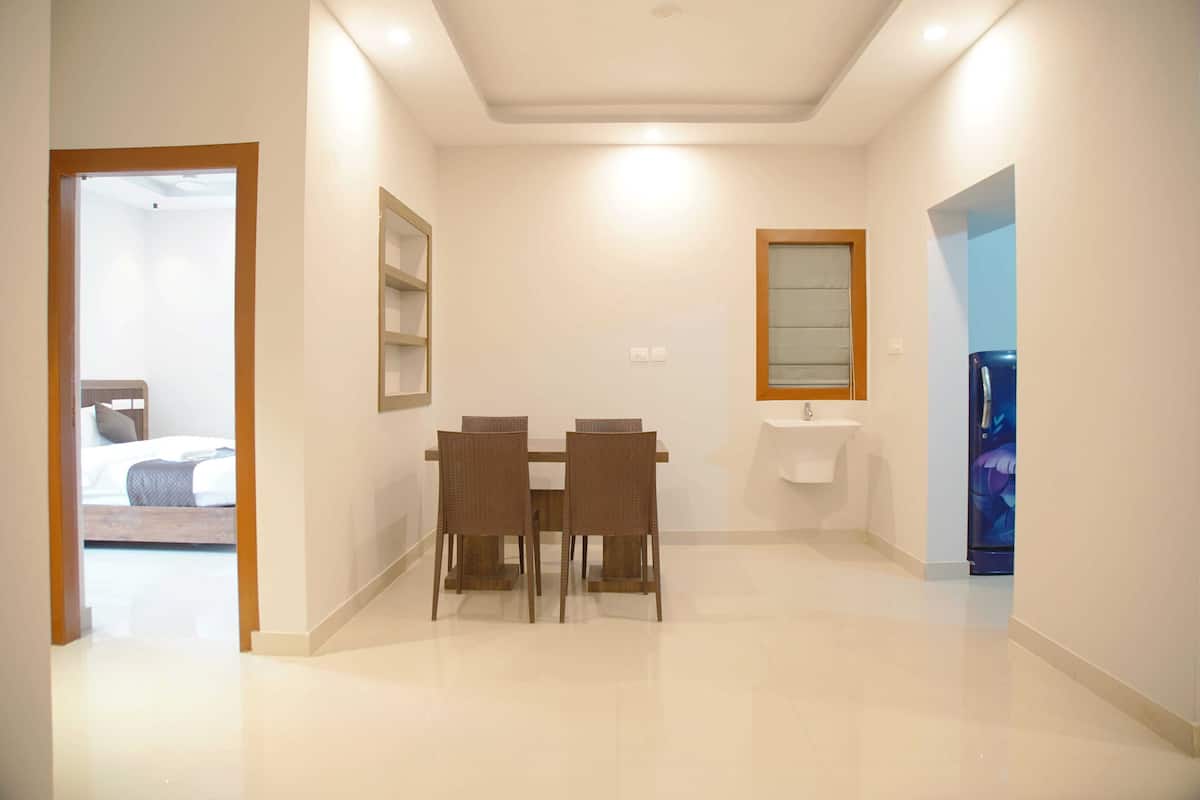 Quarto de hotel com área de jantar, cama, banheiro e vista para o exterior.