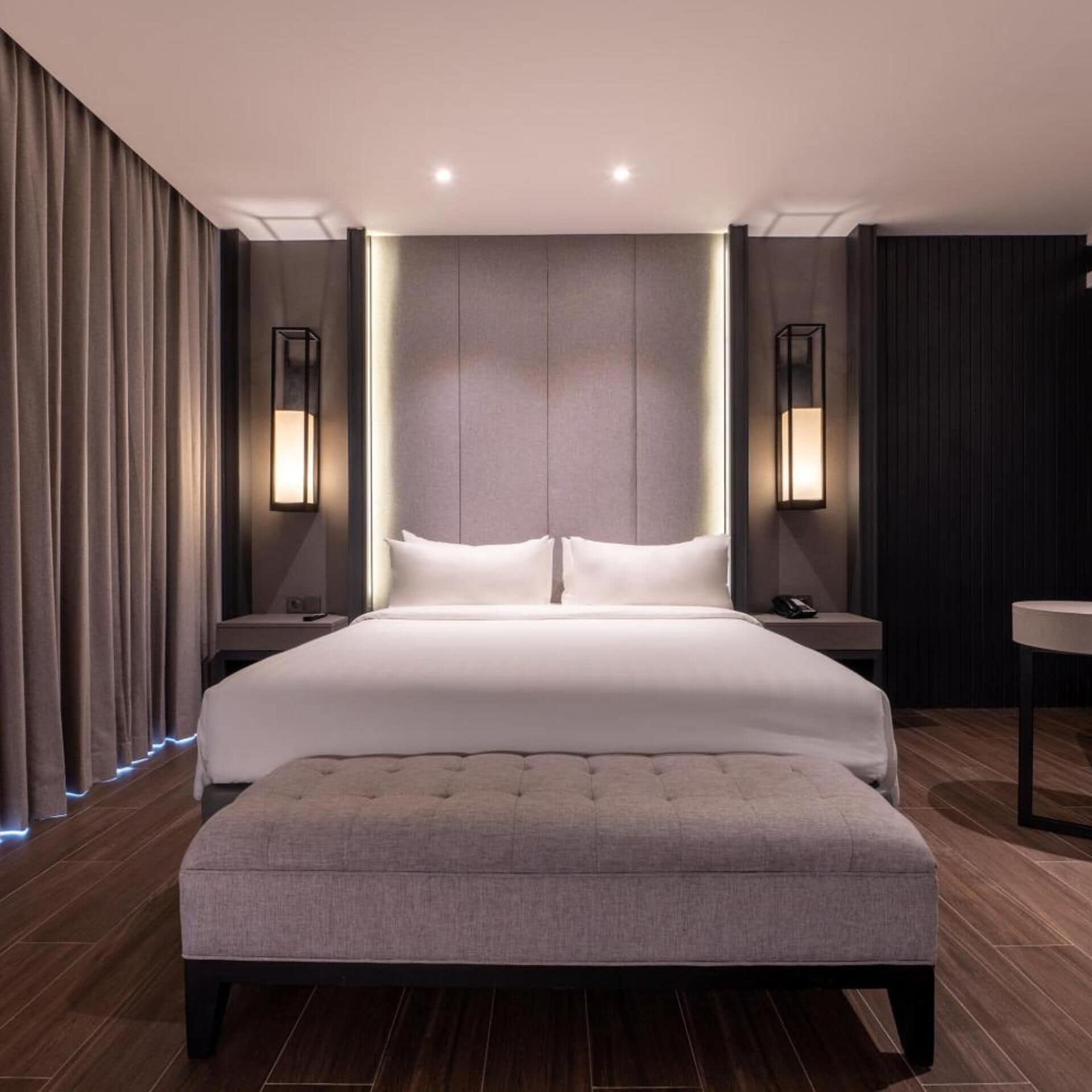 Quarto moderno com uma cama grande, abajures e um banco.