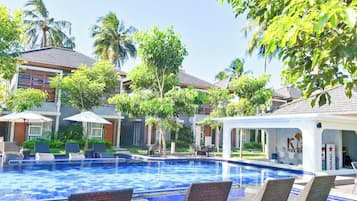 Piscina com espreguiçadeiras, palmeiras e um edifício com a inscrição 'K Pool & Spa'.
