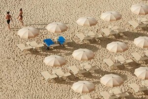 Uma praia com vários guarda-sóis e espreguiçadeiras.