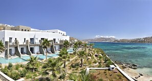 Um resort com piscina, edifícios brancos e vista para o mar.