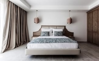 Quarto com uma cama grande, duas mesas de cabeceira, um guarda-roupa e duas luminárias pendentes.