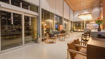 Um interior moderno com balcão de atendimento, área de estar e grandes janelas.