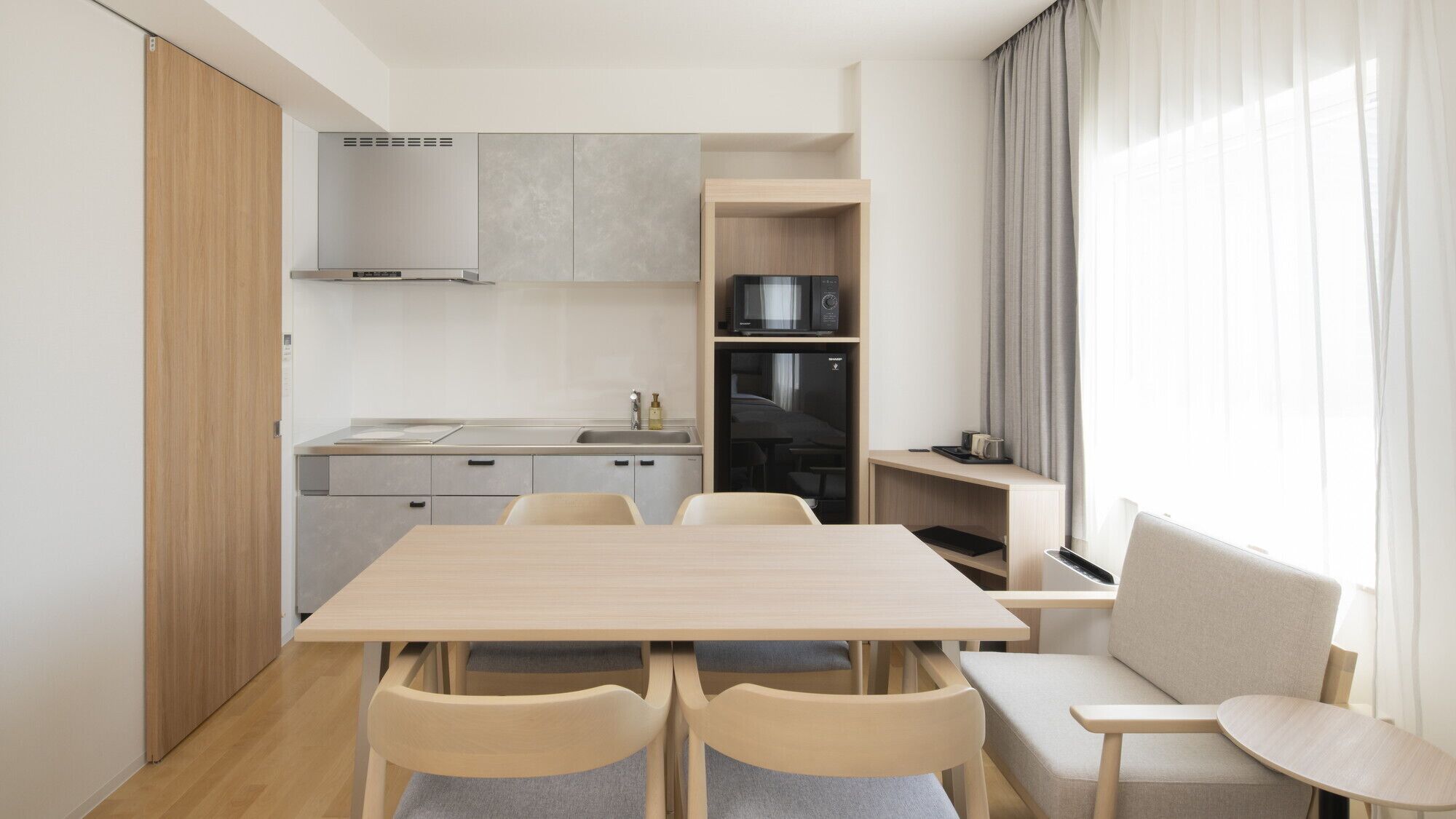 Uma cozinha compacta com área de refeições, incluindo uma mesa, cadeiras e forno embutido.