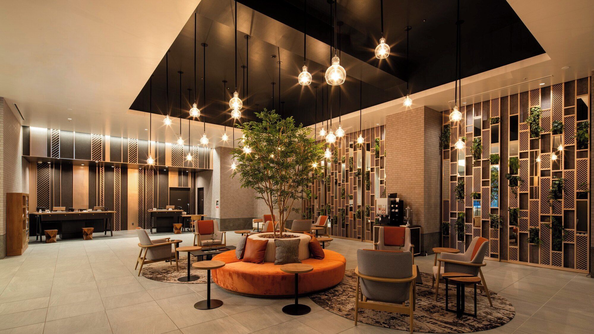 Um lobby moderno com área de estar central, balcão de recepção e parede com jardins verticais.