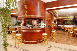 Uma área de bar com banquetas, balcão e um grande pilar de madeira.