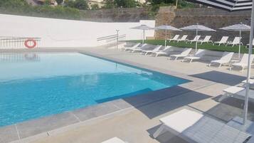 Piscina com espreguiçadeiras e guarda-sóis.