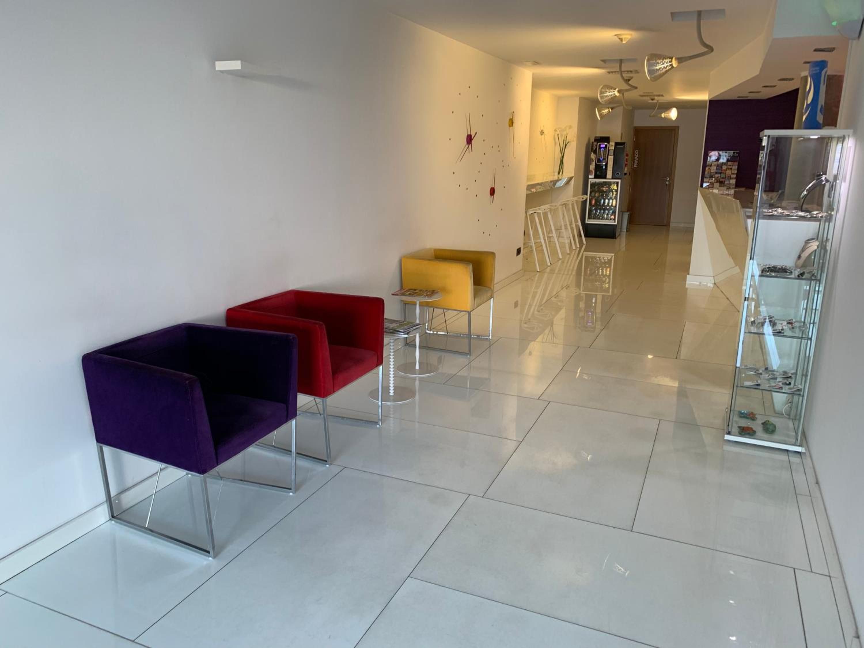 Um lobby moderno com balcão de recepção, máquina de vendas automática e uma vitrine de vidro.