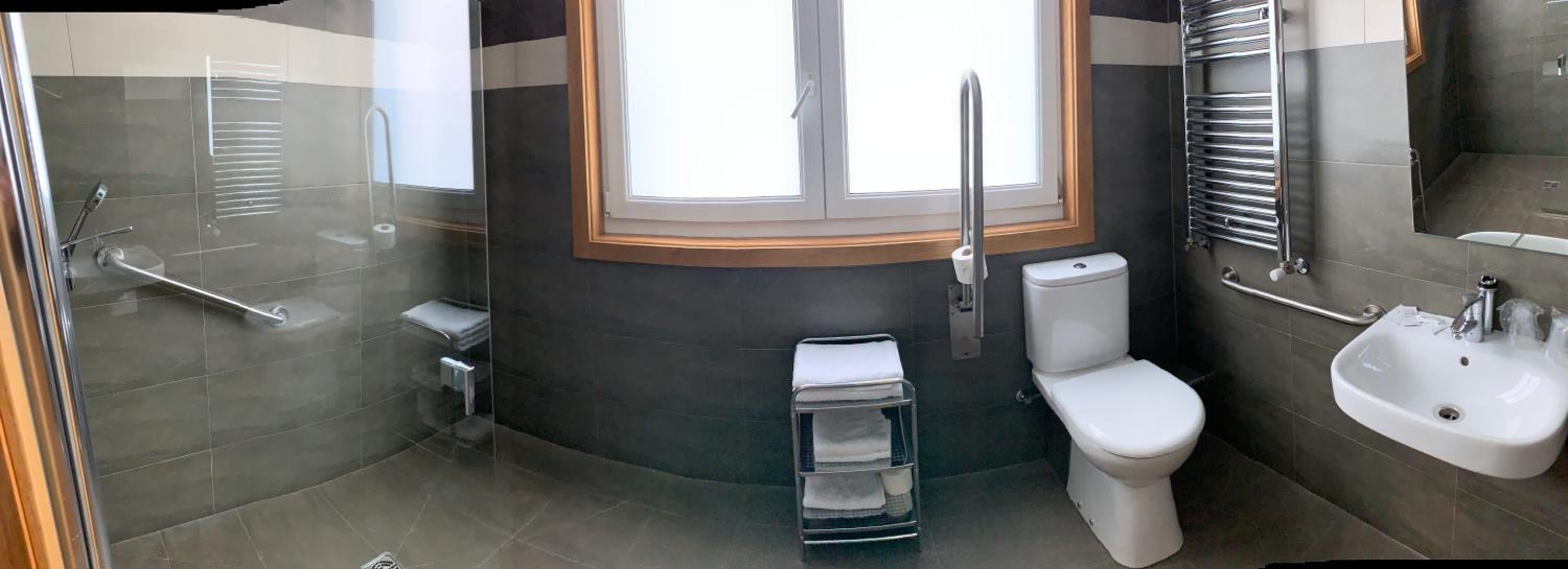 Uma casa de banho moderna com cabine de duche em vidro, sanita, lavatório e barra de toalhas.