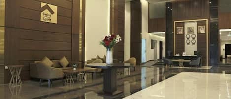 Um lobby moderno com balcão de recepção, área de estar e amplo piso de mármore.