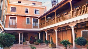 Um pátio com varanda de madeira, vasos de plantas e piso de azulejos.