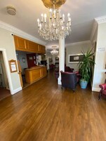 Um hall espaçoso com uma receção em madeira, um candelabro e uma planta em vaso.