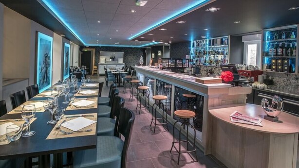 Uma área de bar moderna com um balcão longo, banquetas e um espaço para o barista.