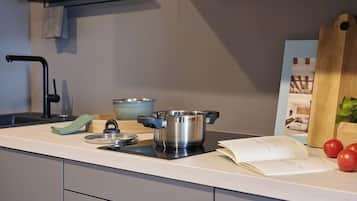 Uma cozinha com fogão, panelas, um livro e uma tábua de corte.